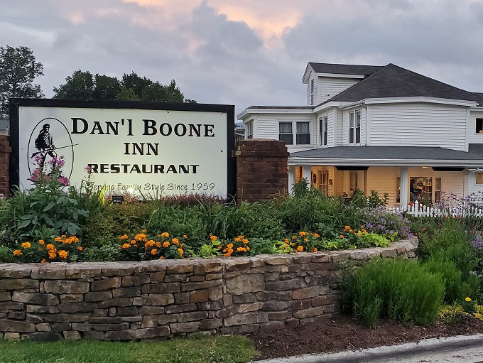 The white clapboard building with its picket fence and American flag stands as a testament to timeless Appalachian hospitality in downtown Boone.