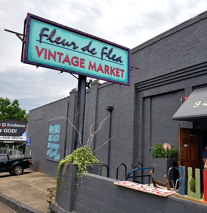 The turquoise sign beckons like a vintage siren song, promising treasures behind those brick walls that your modern big-box stores couldn't dream of housing.