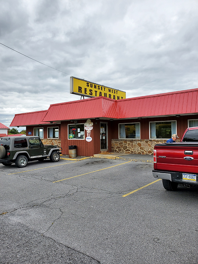 The iconic red roof and stone facade of Sunset West Restaurant stands as a beacon of comfort food in Pleasant Gap, where hungry travelers find their breakfast destiny.