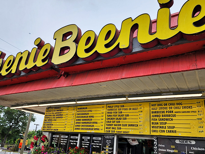 The iconic pink-and-yellow Weenie Beenie stands proudly against a blue Virginia sky, like a time capsule of American roadside charm waiting to be discovered.