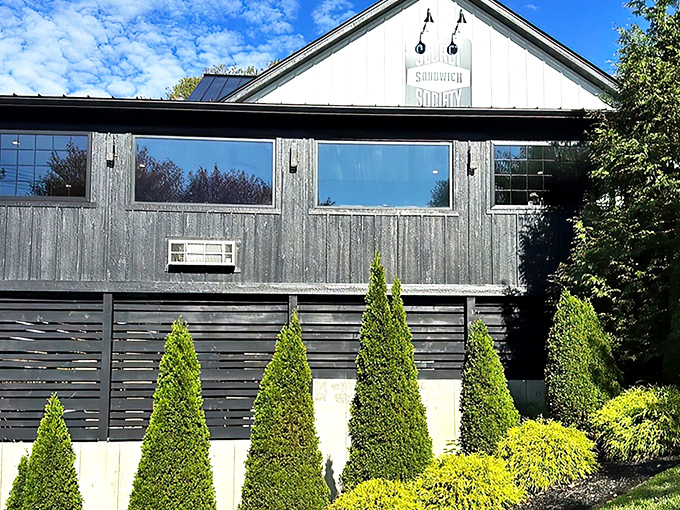 The charming white farmhouse exterior of Secret Sandwich Society stands like a beacon of hope for hungry travelers. Sandwich salvation awaits inside.