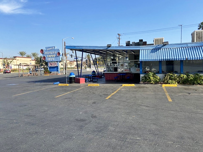 The blue-striped awning of George's Drive-In stands like a beacon of burger paradise against the California sky, promising delicious nostalgia with every order.