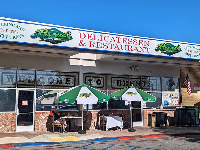 The classic storefront of Brent's Deli beckons with its nostalgic charm. Those red umbrellas aren't just for show&mdash;they're gateways to sandwich paradise.