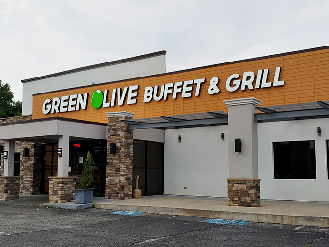 The golden-orange facade of Green Olive Buffet stands like a beacon to hungry travelers. Stone accents and modern signage promise culinary adventures within.
