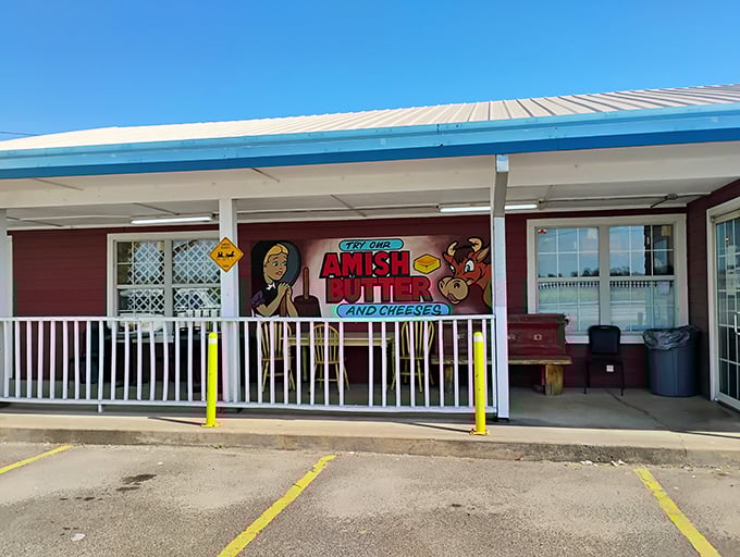 The unassuming burgundy exterior with its "Try our Amish Butter and Cheeses" sign promises treasures within that the simple facade modestly conceals.