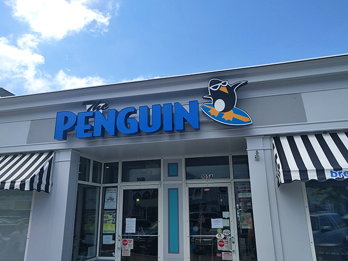 The Penguin's cheerful blue sign and tuxedoed mascot stand ready to welcome hungry beachgoers&mdash;like a breakfast ambassador promising morning delights just steps from the sand.