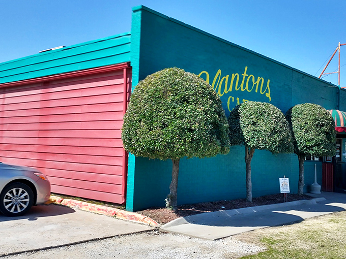 The vibrant turquoise and red exterior of Clanton's Caf&eacute; stands as a colorful beacon on Route 66, promising comfort food treasures within those striped awnings. 