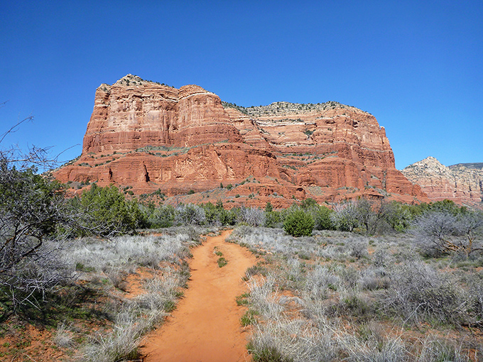 Nature's red carpet rolls out before you, leading to Bell Rock's majestic silhouette against that impossibly blue Arizona sky.