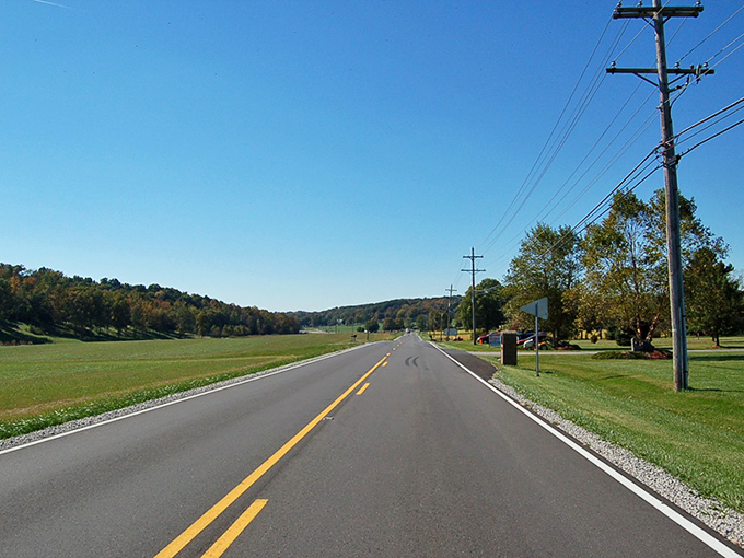 Nature's corridor awaits as autumn begins its slow dance along Highway 62. The limestone walls stand sentinel while trees prepare their grand finale.