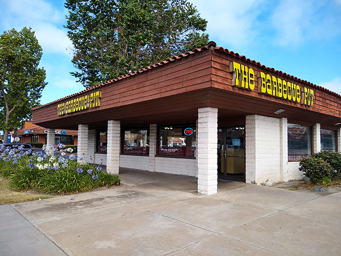 The unassuming exterior of The Barbecue Pit stands like a beacon of hope for hungry travelers. That yellow sign promises smoky salvation within those humble walls.