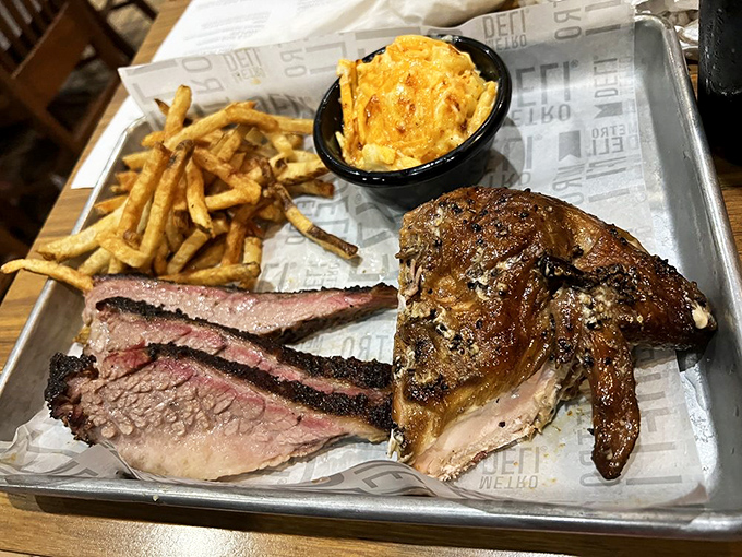 Meat trinity: brisket, chicken, and pulled pork sharing a tray like old friends. That mac and cheese is the kind grandmothers fight over at family reunions.