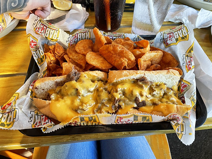 Melted cheese cascades down this cheesesteak like a yellow waterfall of happiness. The kind of sandwich that demands both napkins and respect.