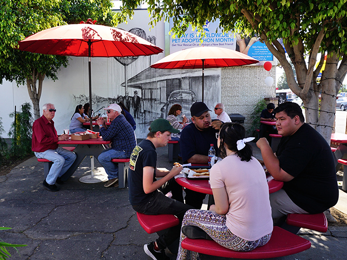 Under cheerful red umbrellas, strangers become friends united by the universal language of exceptional hot dogs.