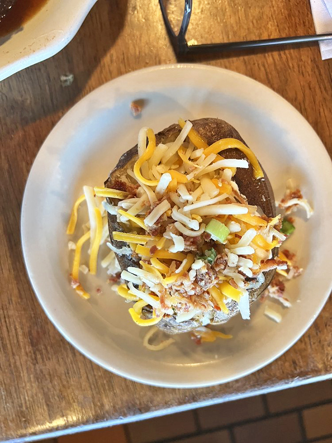 The loaded baked potato arrives like a mountain of comfort &ndash; cheese cascading down the sides like delicious lava from a carb volcano.