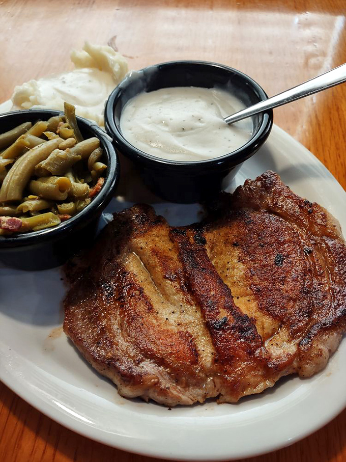 A pork chop with the perfect sear, flanked by green beans and mashed potatoes&mdash;the holy trinity of Southern comfort on a plate.