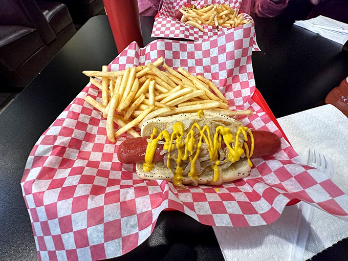 A Polish sausage dressed with mustard alongside golden fries. Simple pleasures executed perfectly&mdash;the way street food should be.