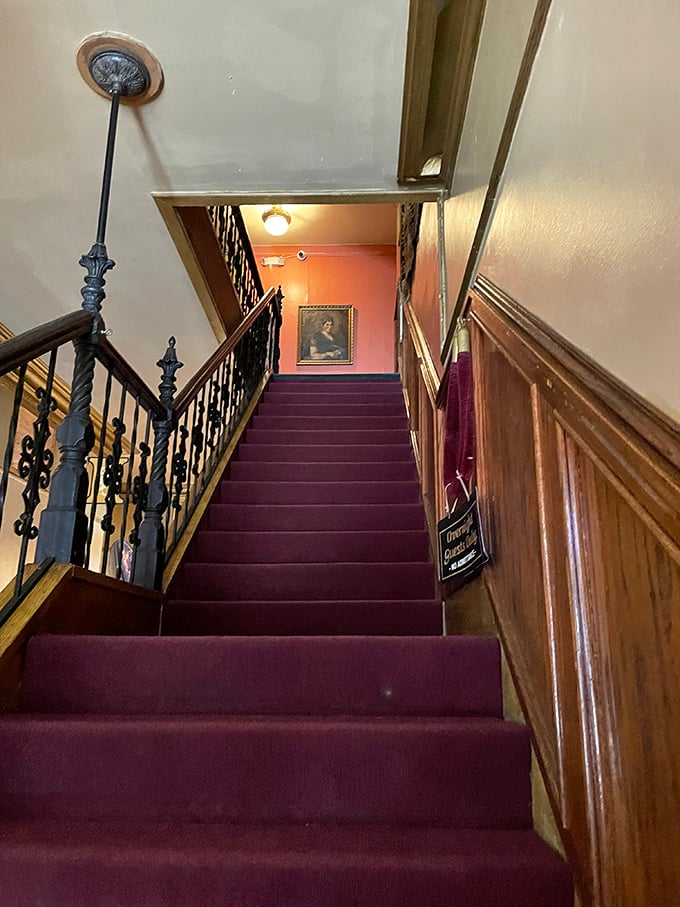 The crimson-carpeted staircase leads to the mansion's most active paranormal areas. Each step brings you closer to what might be waiting at the top.