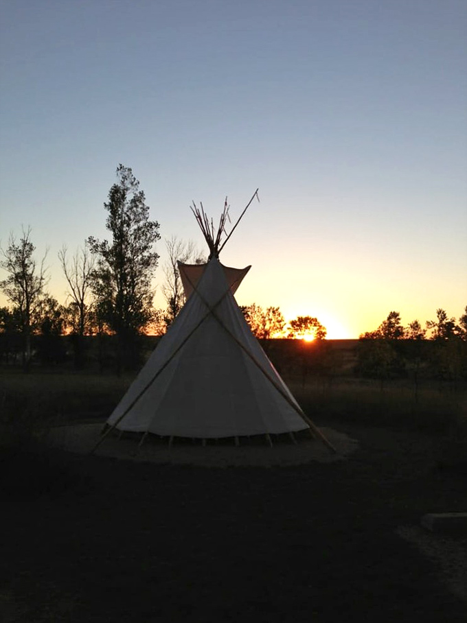 A tipi silhouetted against the sunset sky creates a moment of timeless connection to the land's indigenous heritage. Pure magic.