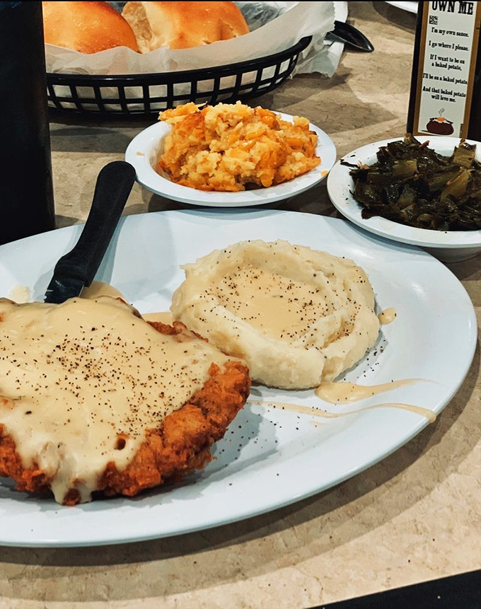 Country fried steak smothered in creamy gravy &ndash; where pepper-speckled comfort meets mashed potato mountains and collard green valleys.