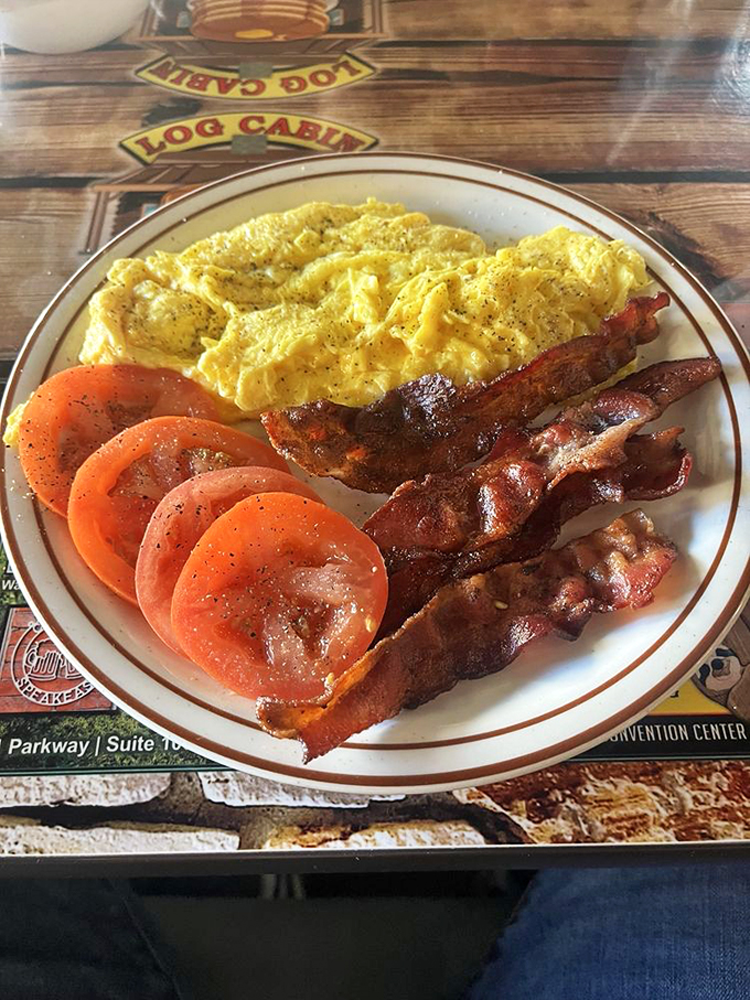 A breakfast plate that speaks the universal language of morning satisfaction: golden eggs, crispy bacon, and juicy tomatoes.
