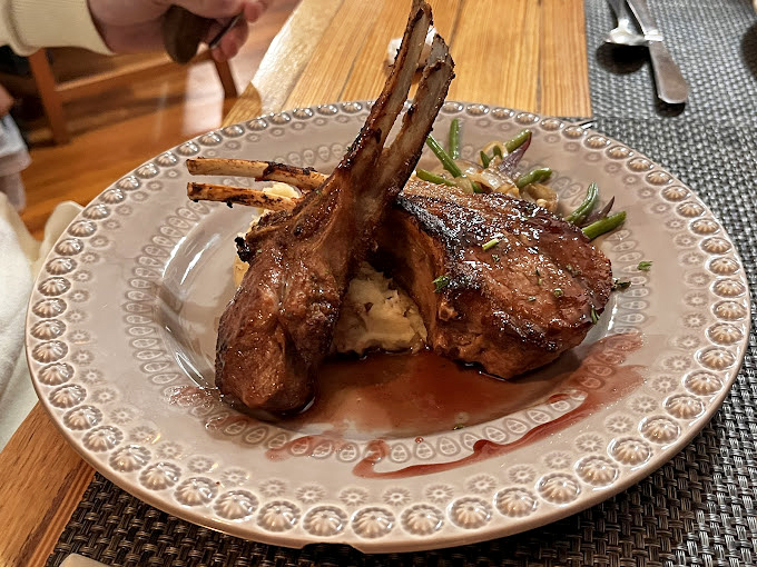 Lamb chops positioned like the sails of a delicious ship, navigating a sea of mashed potatoes and savory reduction. Even the bones are dressed for the occasion.