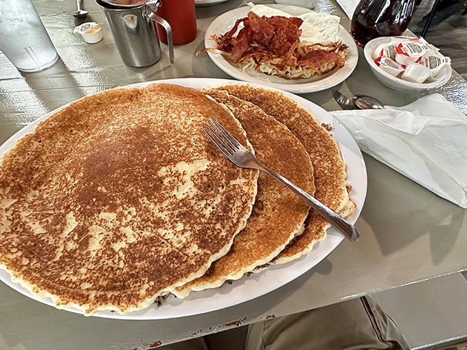 Pancakes so massive they deserve their own area code, with perfect golden-brown surfaces that could double as landing pads for butter.