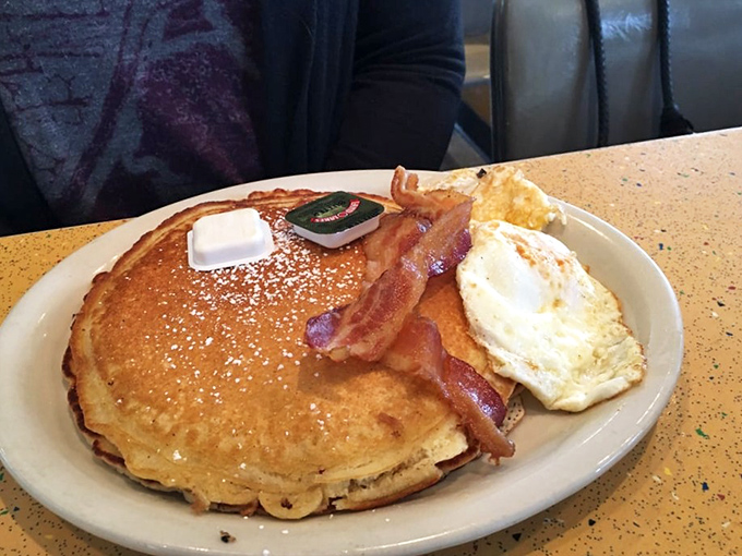 Pancakes so fluffy they could float away if not anchored by that perfect square of butter and strips of bacon standing guard.