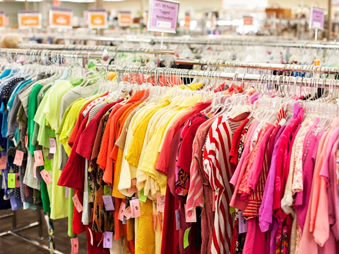 Color-coded clothing racks create a rainbow road through the store, each hue a different chapter in the never-ending thrift story.