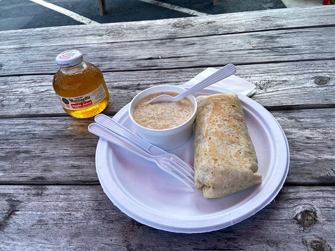 A breakfast burrito and apple juice on a picnic table&mdash;proof that sometimes the best dining room is wherever you can balance a plate outdoors.