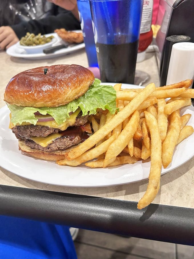A double cheeseburger so perfectly constructed it could have its own architectural blueprint, with fries standing at attention nearby.