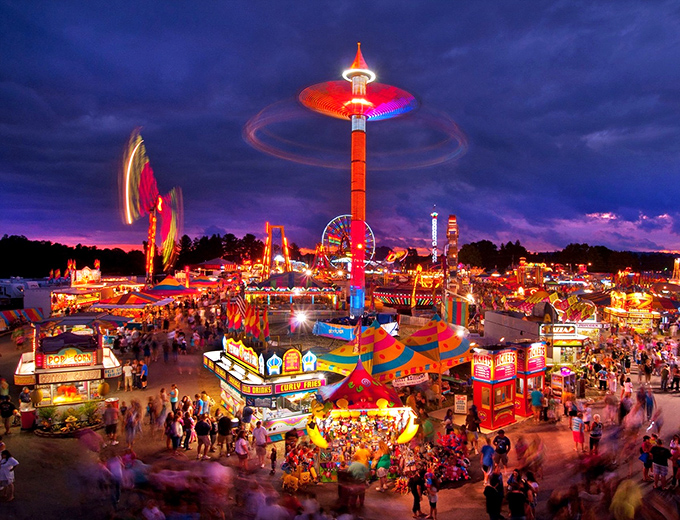 The State Fair transforms quiet countryside into a neon-lit wonderland where funnel cakes and Ferris wheels remind us all of simpler pleasures.