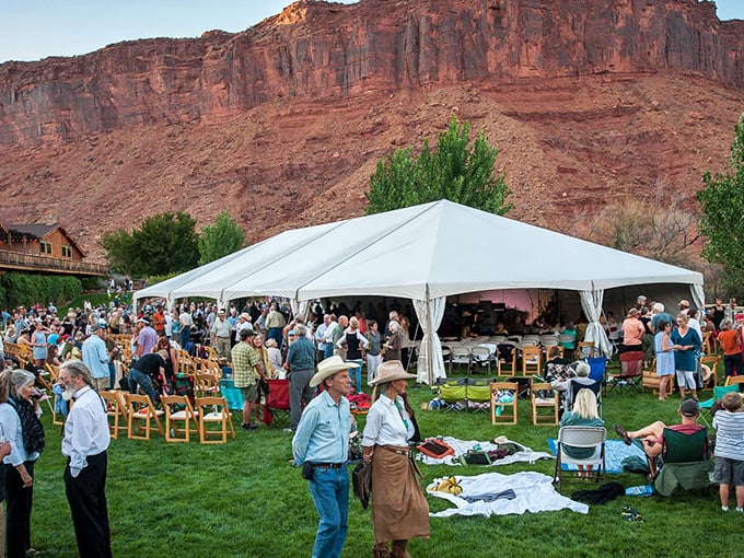 Desert gatherings under white tents with red rock backdrops—where cowboy hats and Tevas constitute the local formal wear.