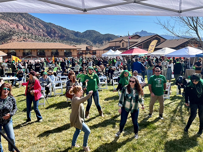 Locals and visitors alike gather for what appears to be Springdale's version of a block party. Green attire suggests St. Patrick's Day celebrations with red rock flair.