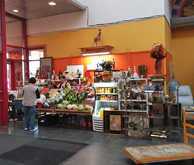 Fresh produce mingles with decorative figurines in this eclectic corner, where practical shopping meets whimsical browsing in perfect harmony.