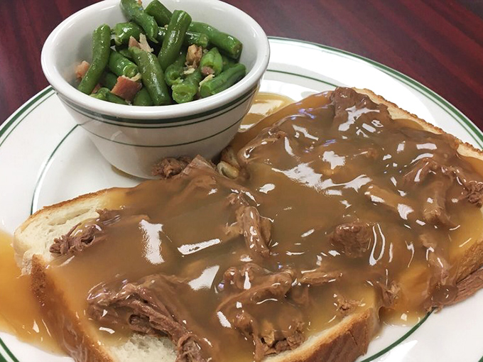 The hot beef sandwich&mdash;tender meat on pillowy bread, blanketed in gravy that cascades over the edges. Green beans stand guard against total indulgence.