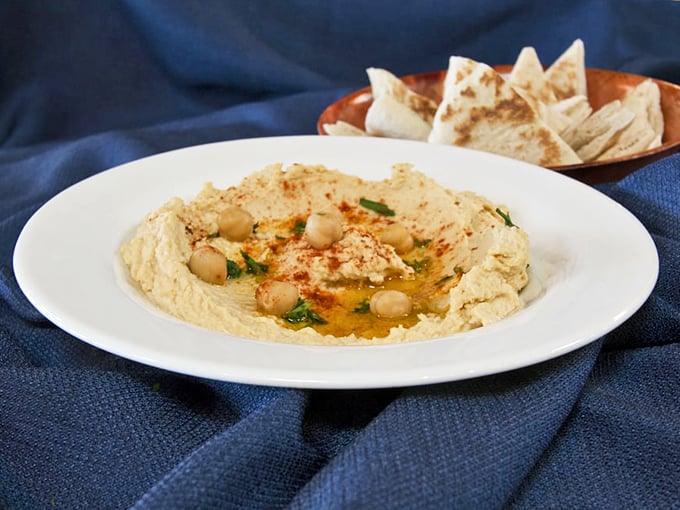 Hummus so creamy it could make velvet jealous, crowned with chickpeas and a pool of olive oil. This isn't a dip, it's a revelation.
