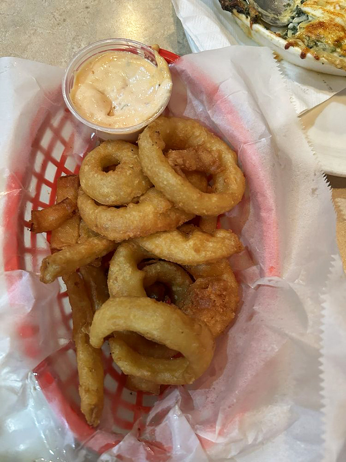 Onion rings stacked like delicious golden halos, with dipping sauce that makes you question why you'd ever eat onions any other way.