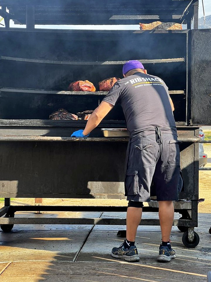 Where the magic happens. The pitmaster tends to his smoker with the focus and dedication of a NASA engineer preparing for launch.
