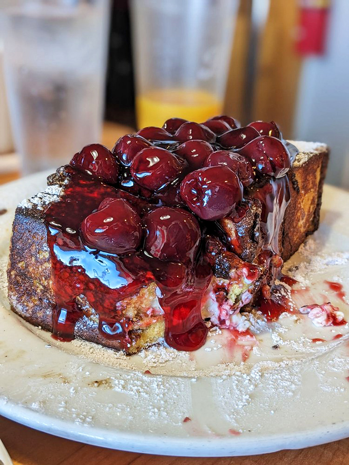 French toast that's having an identity crisis as dessert, crowned with cherries in a sweet syrup lake &ndash; breakfast or dessert? Yes.