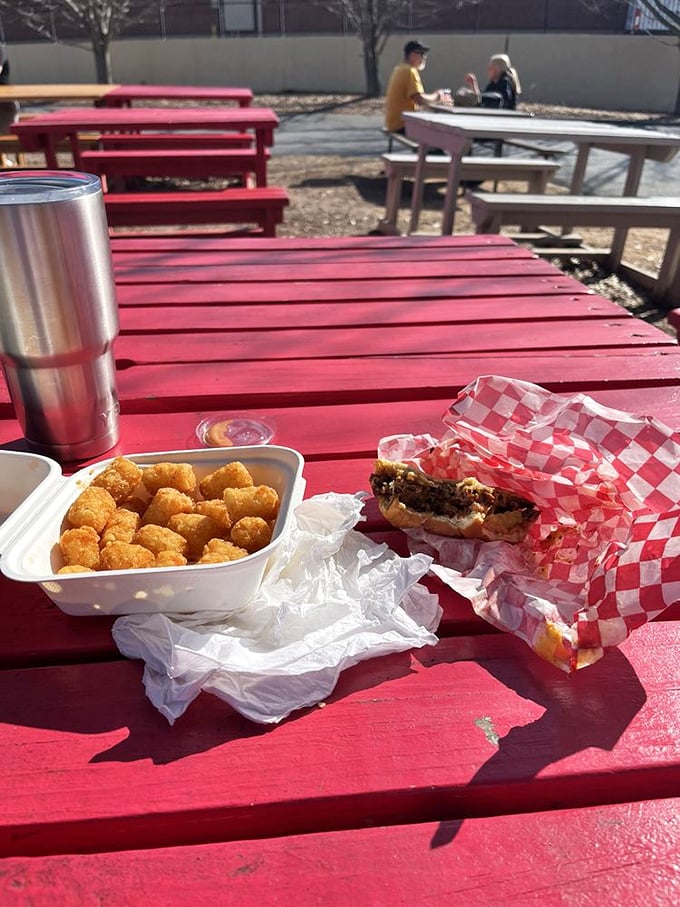 Outdoors dining with tater tots and a burger&mdash;nature's perfect pairing. Red picnic tables: the unofficial color of good times and great food.