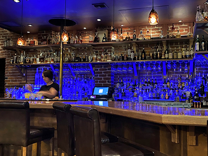 The bar glows blue like a sapphire necklace, promising liquid treasures that pair perfectly with protein. Cocktail alchemy at its finest. 