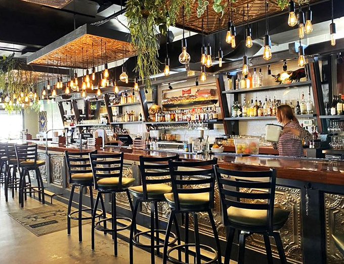 Edison bulbs dangle above a bar that invites lingering, where bartenders mix drinks with the same care the kitchen puts into that famous meatloaf.