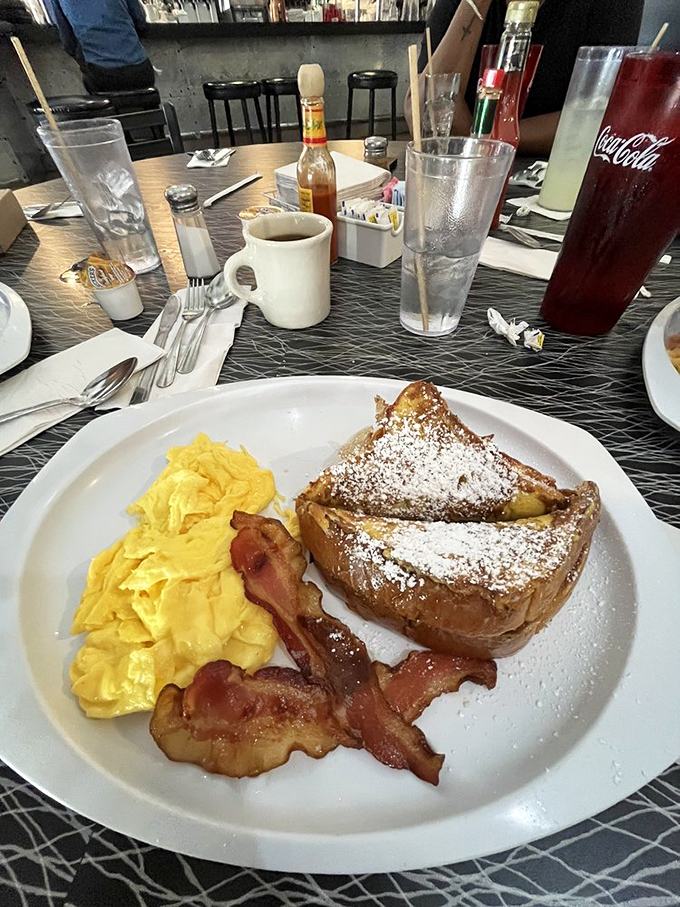French toast dusted with powdered sugar snow, flanked by scrambled eggs and bacon that's achieved that perfect crisp-yet-chewy texture science still can't explain.