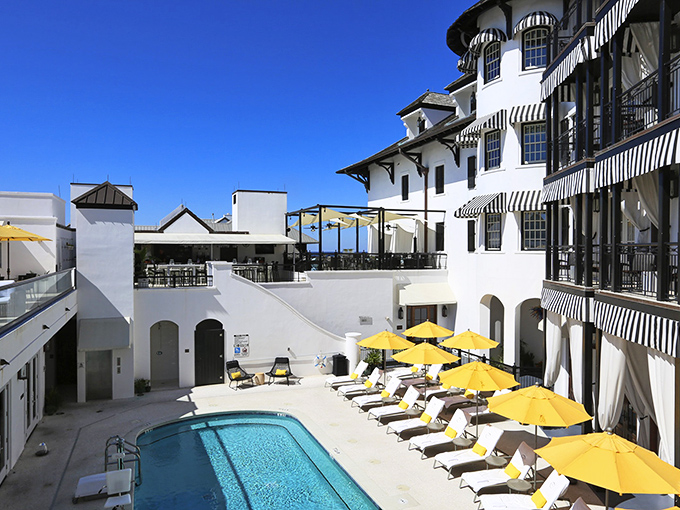 The hotel pool area, where yellow umbrellas stand at attention like sunscreen-coated soldiers guarding against the possibility of not relaxing enough.