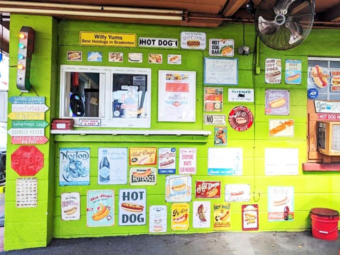 The ordering window, plastered with vintage-style signs, looks like a museum of American hot dog culture. Each sign tells a story of comfort food history.