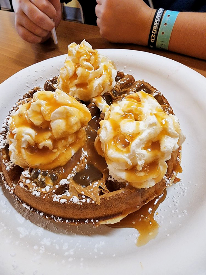 Three pillowy mountains of whipped cream drizzled with caramel atop a golden waffle—a breakfast that makes you wonder why we don't eat dessert first more often.