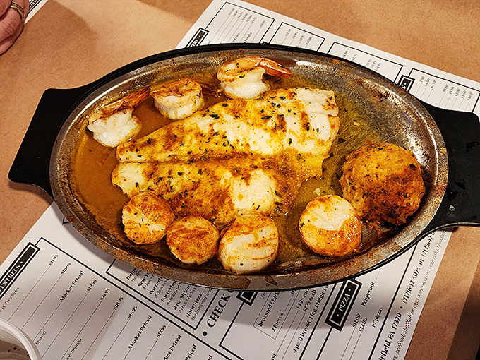 Seafood perfection on a sizzling platter. Those scallops are caramelized to golden perfection, swimming in buttery bliss alongside fish and crab.