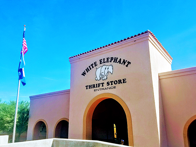 Flags flutter above White Elephant's arched entrance, signaling a diplomatic approach to secondhand shopping. International relations, thrift-style.