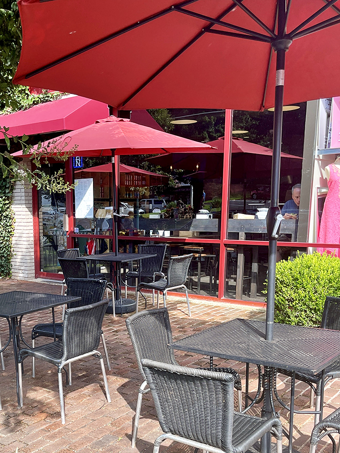 Red umbrellas stand guard over the brick patio, creating an oasis where the only acceptable interruption to conversation is another bite.