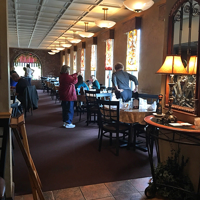 Stained glass windows and warm lighting transform a simple meal into something that feels like dining in a rustic Tuscan villa.